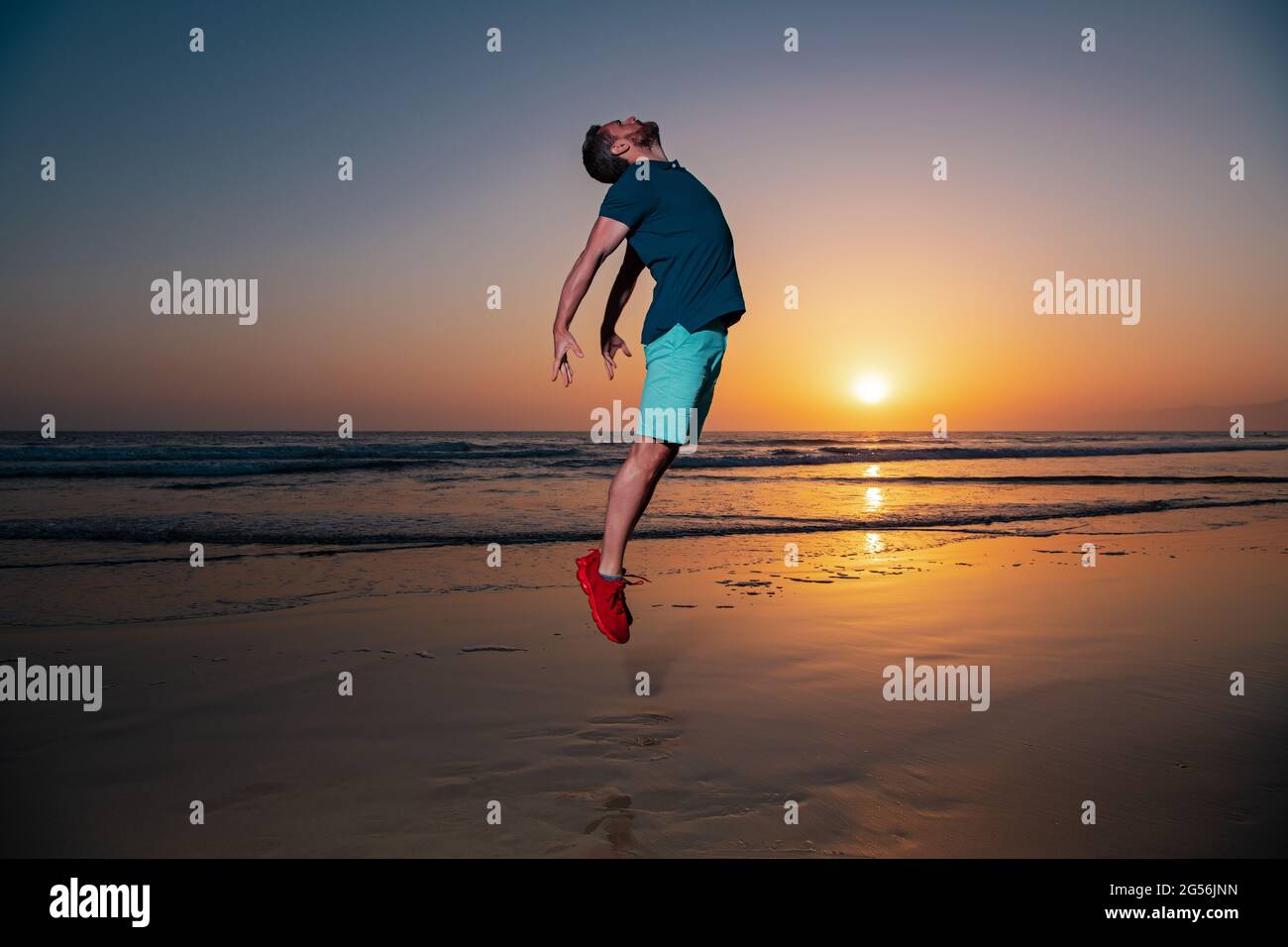 Man jumping on beach, silhouette in the sunset. Feel good and freedom ...