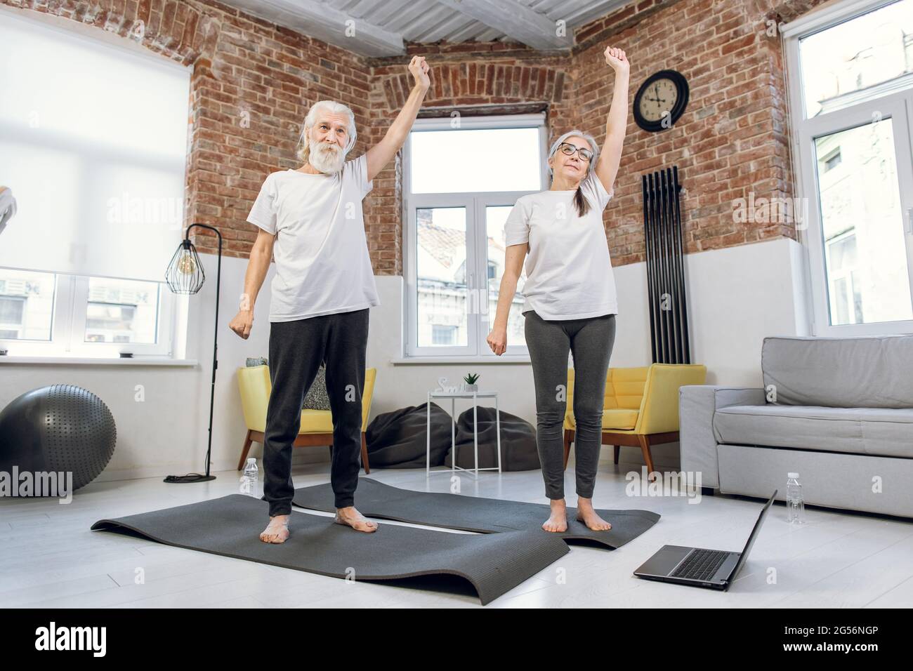 Full length portrait of elderly man and woman standing on yoga man and ...