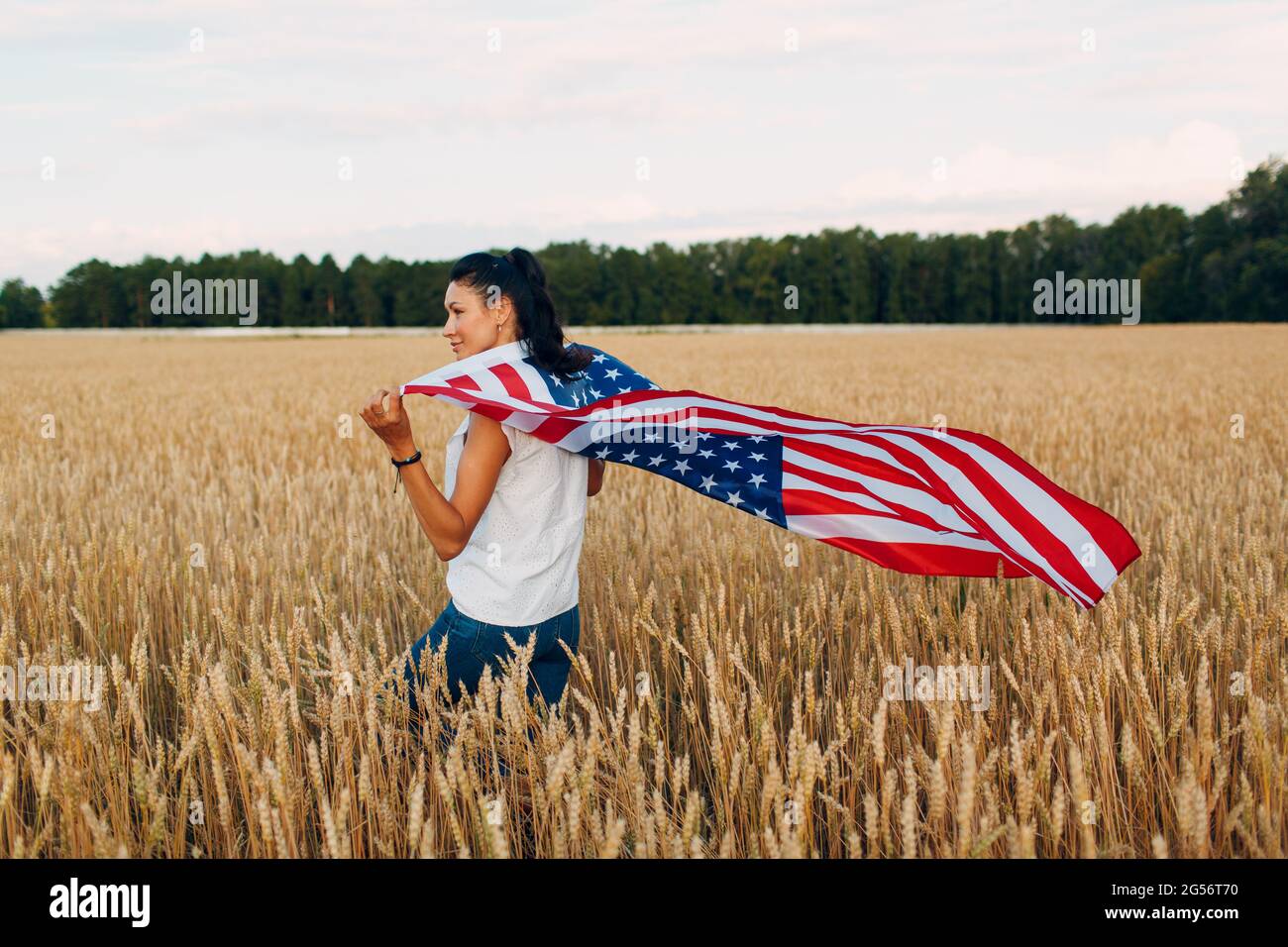 Woman with American flag in wheat field at sunset. 4 of July ...