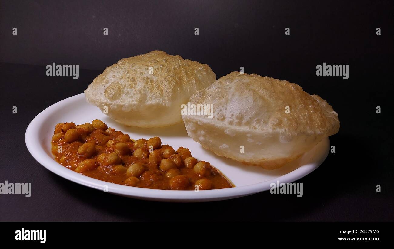 Plastic plate with chole bhature in it, consisting of beans and Indian ...