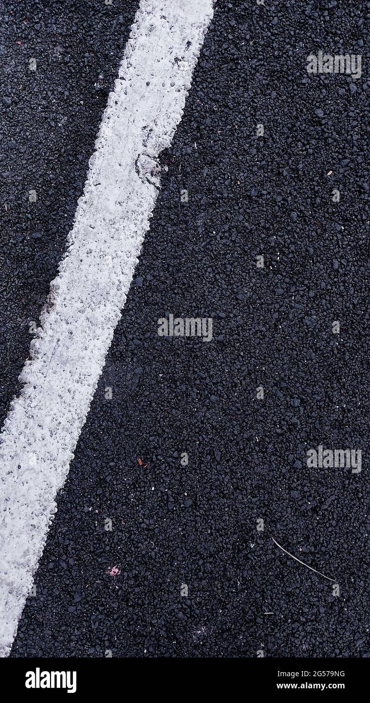 Vertical closeup shot of the white painted lines on an asphalt street ...