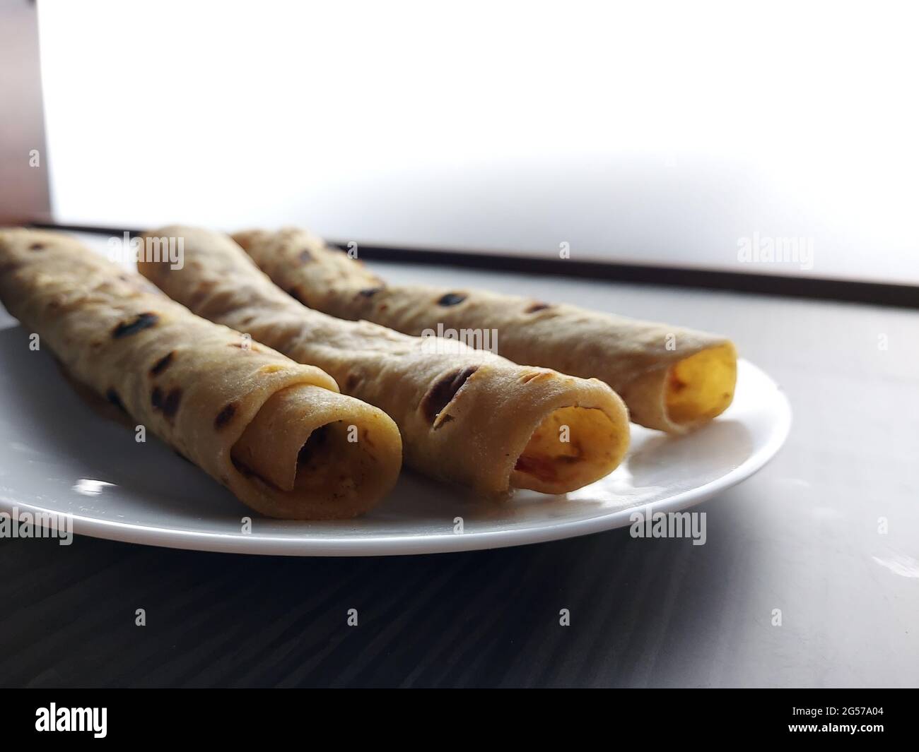 Closeup of three rolled up flatbreads on a white table with bright ...