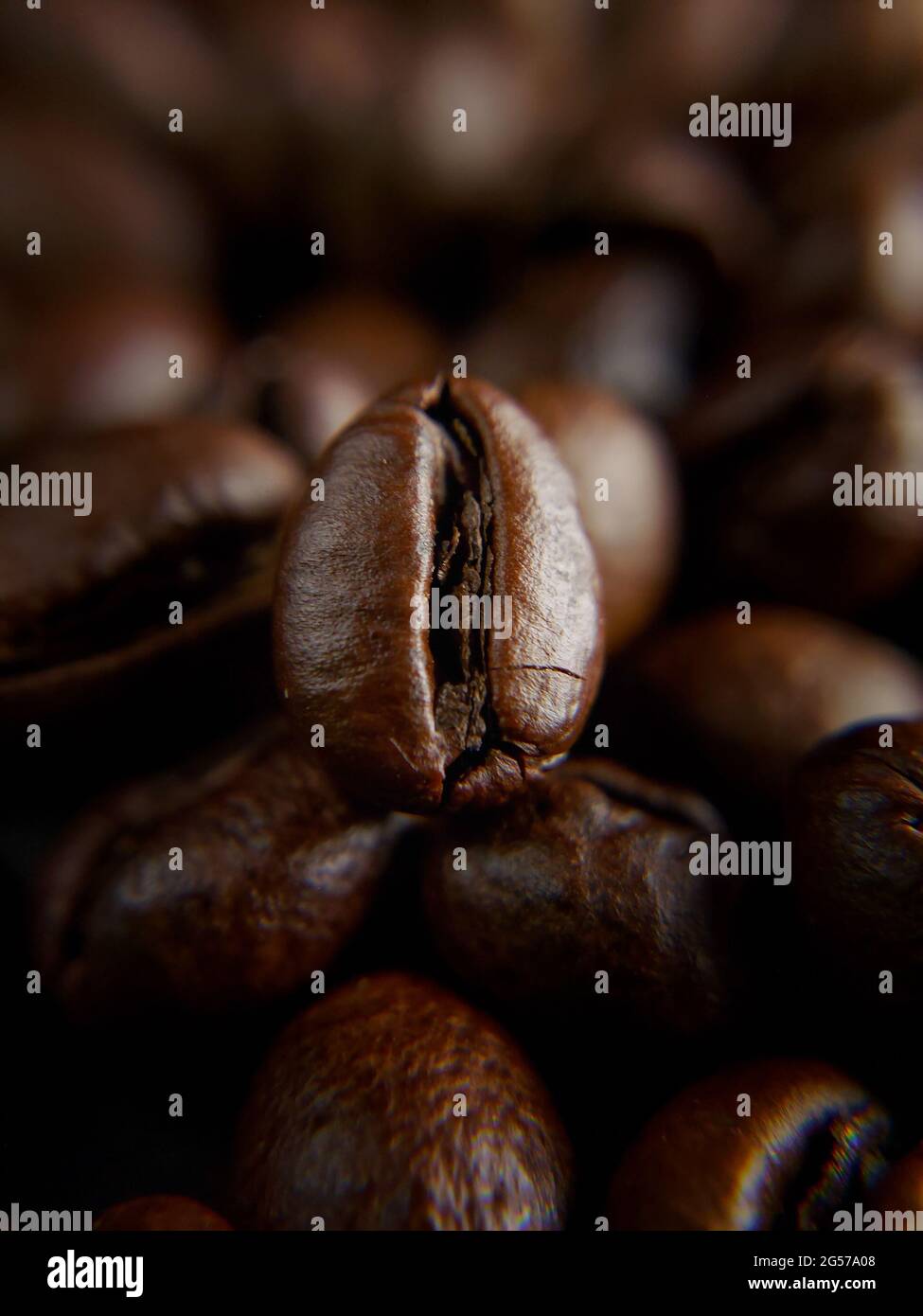Vertical closeup shot of big coffee beans piled together with light ...