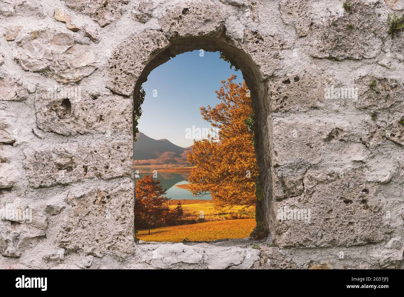 Scenic view of a tranquil lake seen through a stone arch window Stock ...