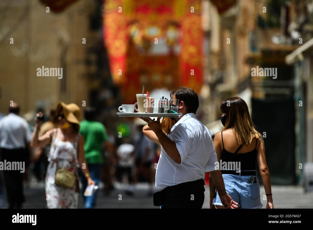 Valletta, Malta. 25th June, 2021. A waiter carries a tray with iced ...