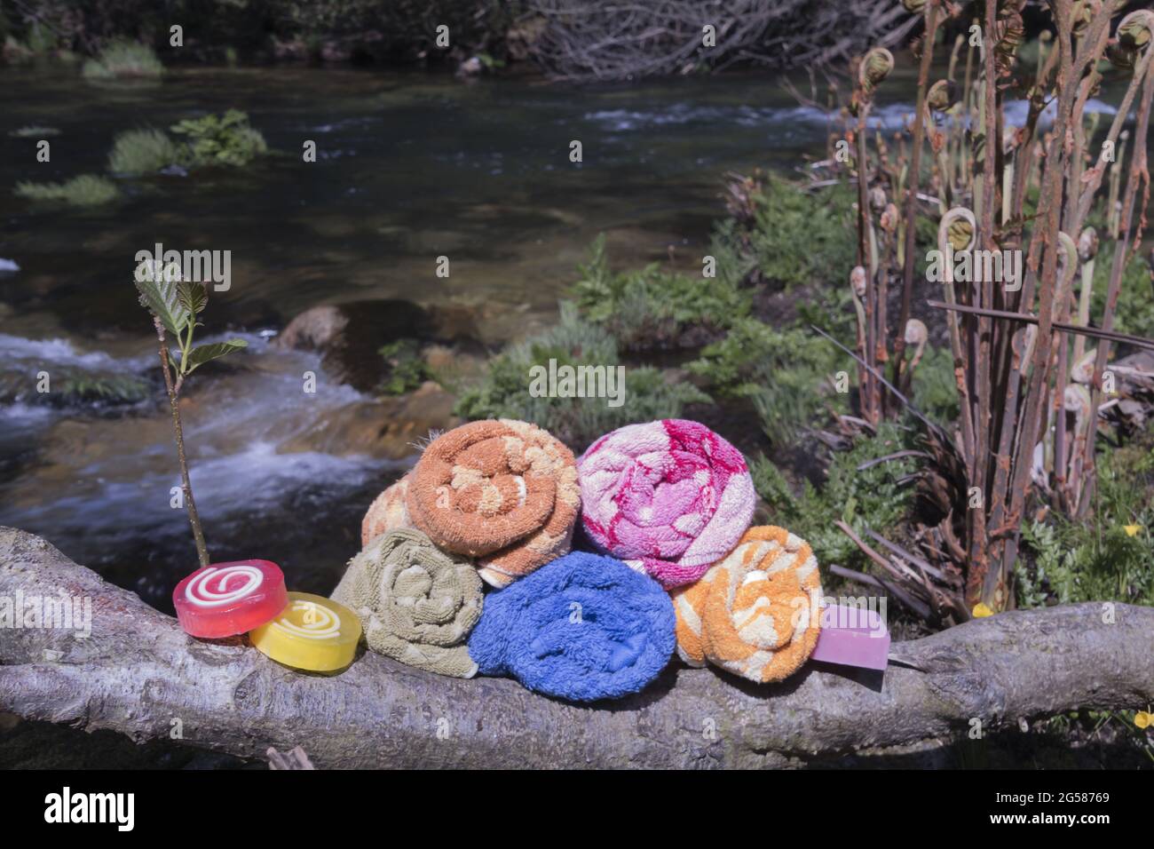 Pile of rolled colorful towels and decorative soaps near a river Stock ...