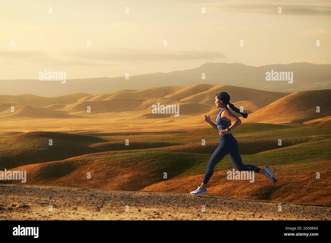 Woman jogging in landscape at sunset Stock Photo - Alamy