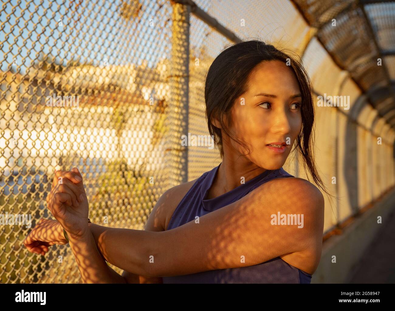 Athlete woman stretching at fence Stock Photo - Alamy