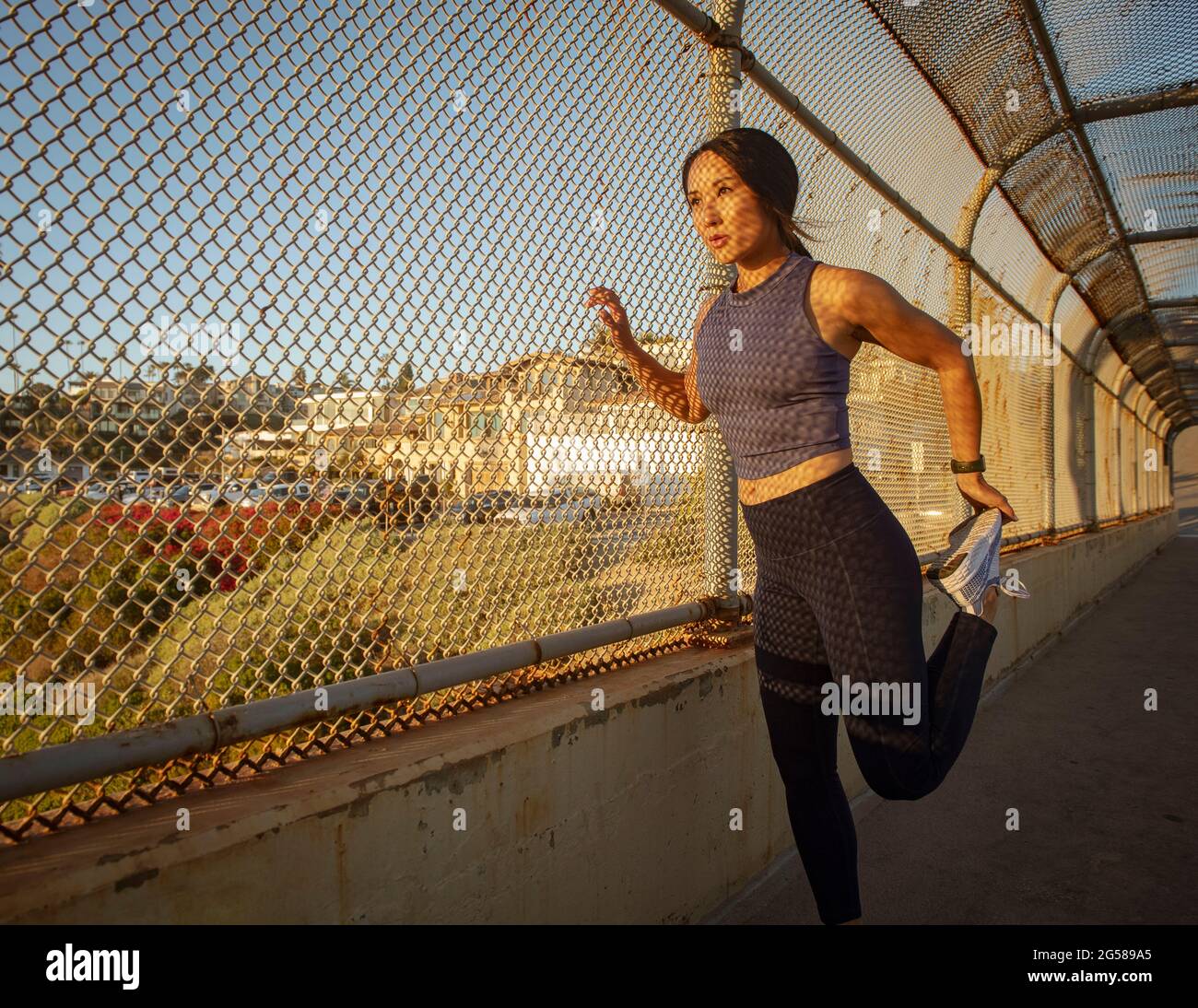 Athlete woman stretching at fence Stock Photo - Alamy