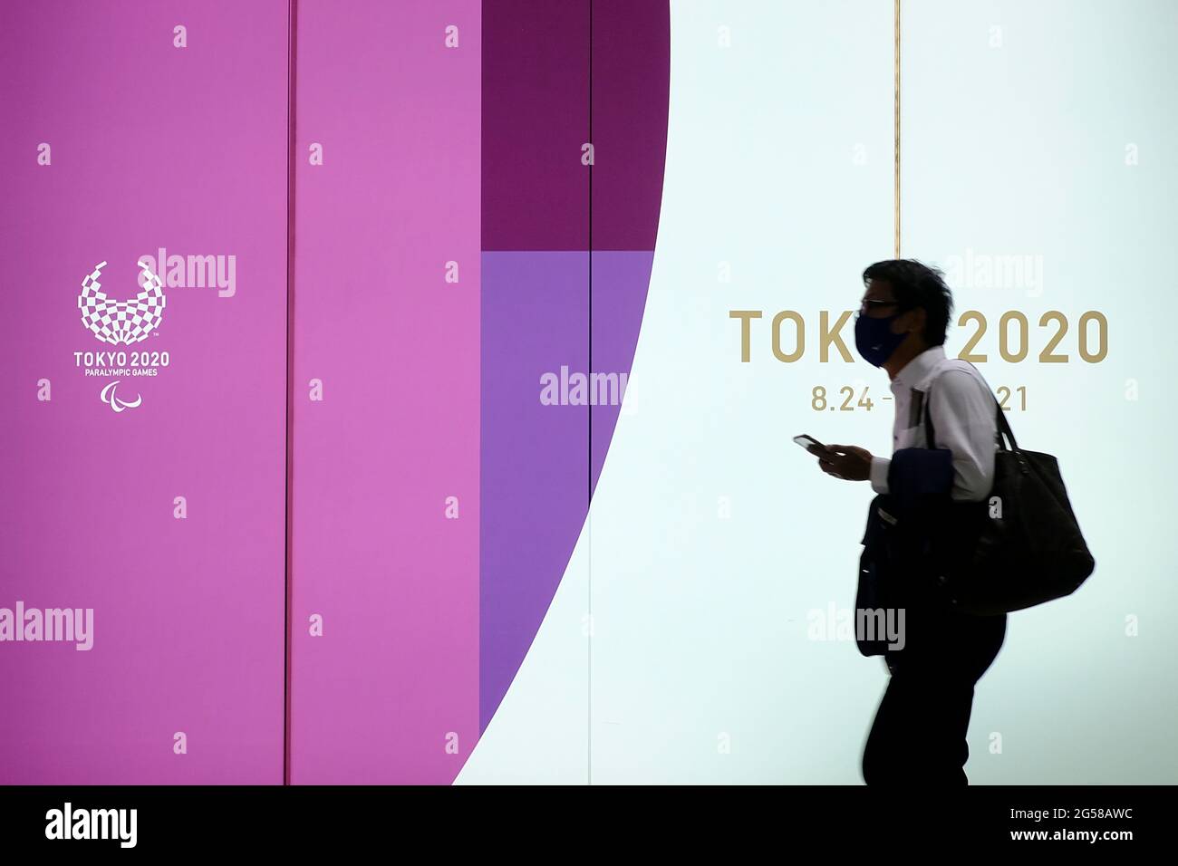 A pedestrian wearing a face mask as a precaution walks by a signage ...