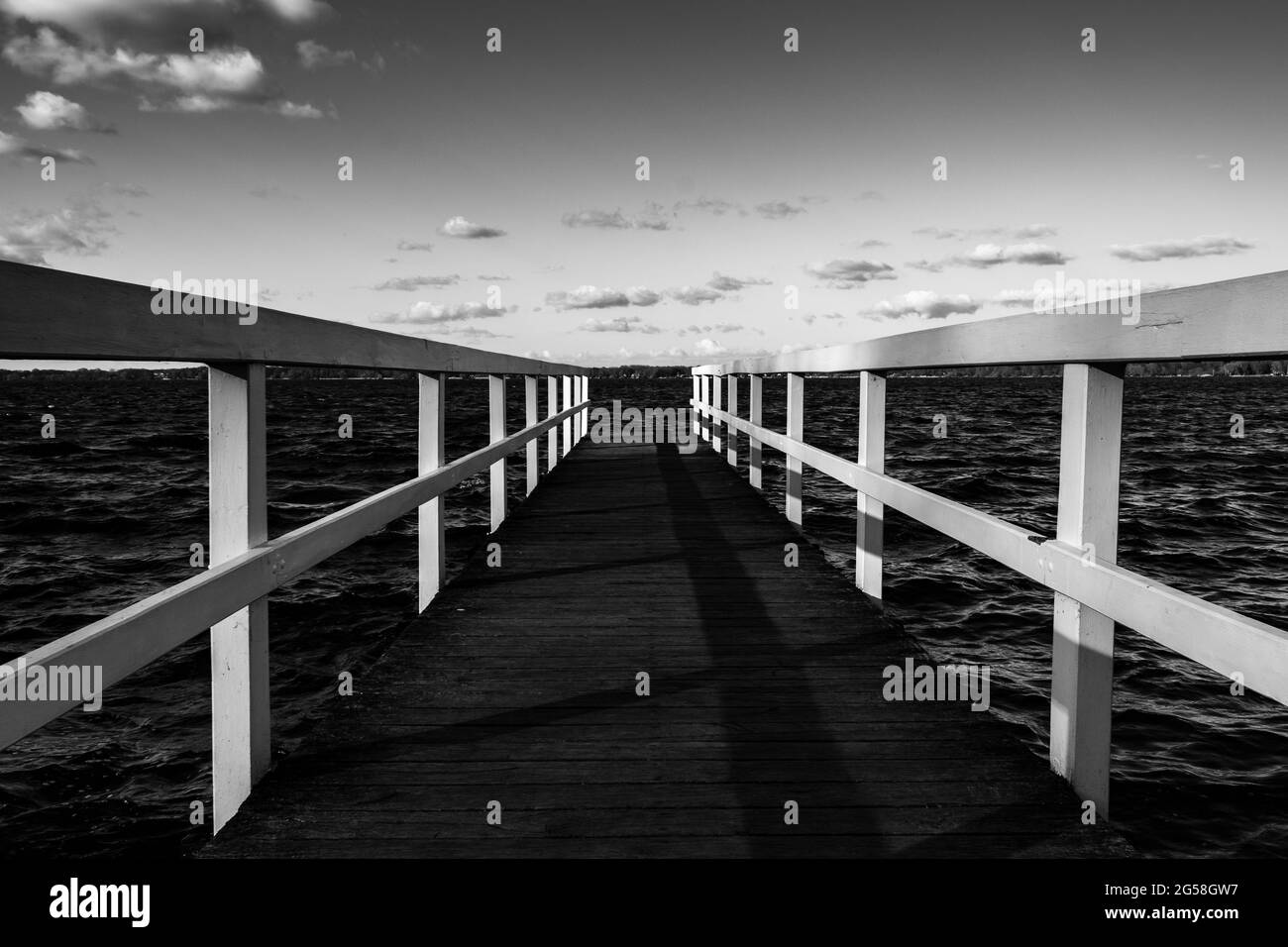 Grayscale shot of a wooden dock by the sea under a cloudy sky Stock ...