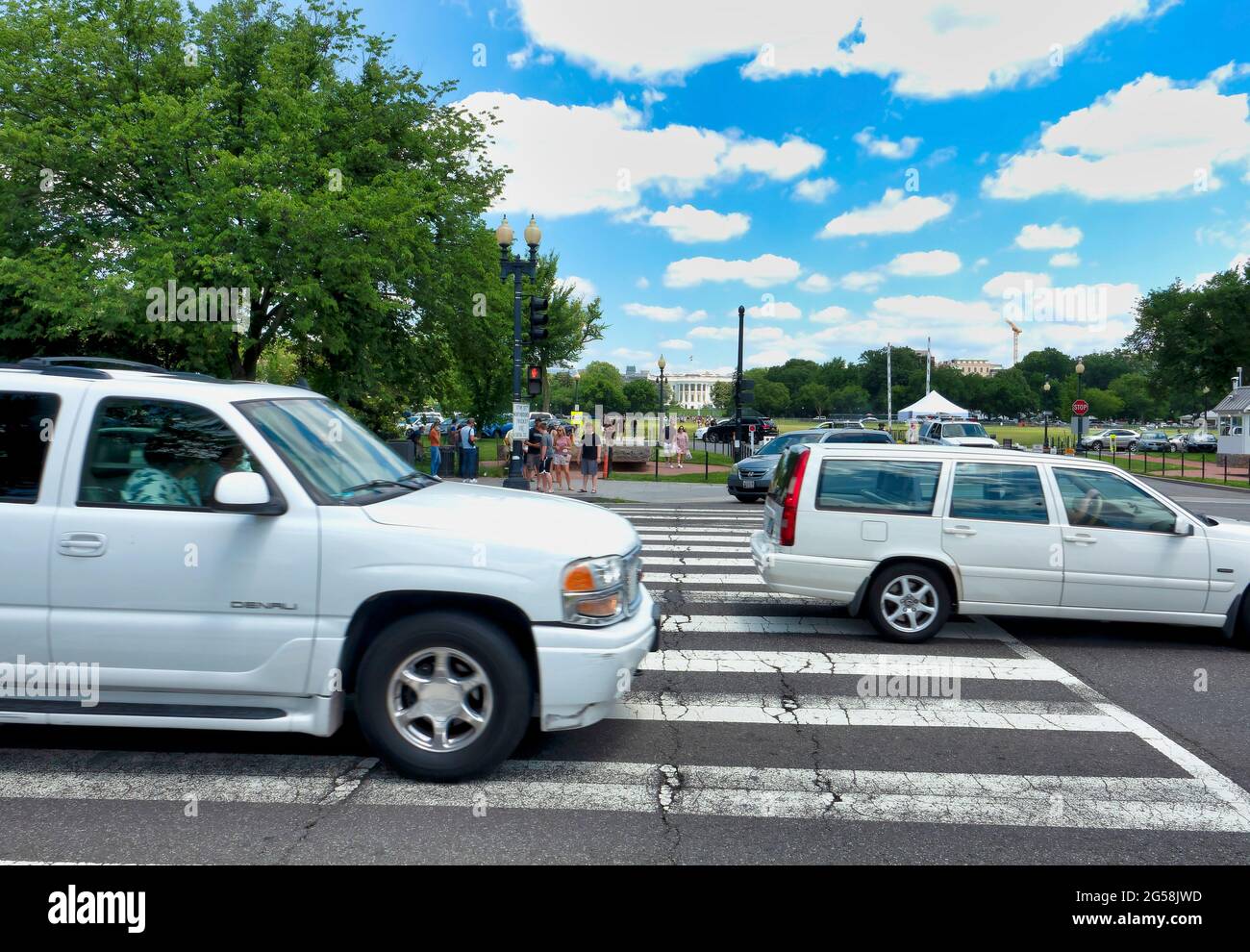 Cars drive through a crosswalk on Constitution Avenue in front of the ...