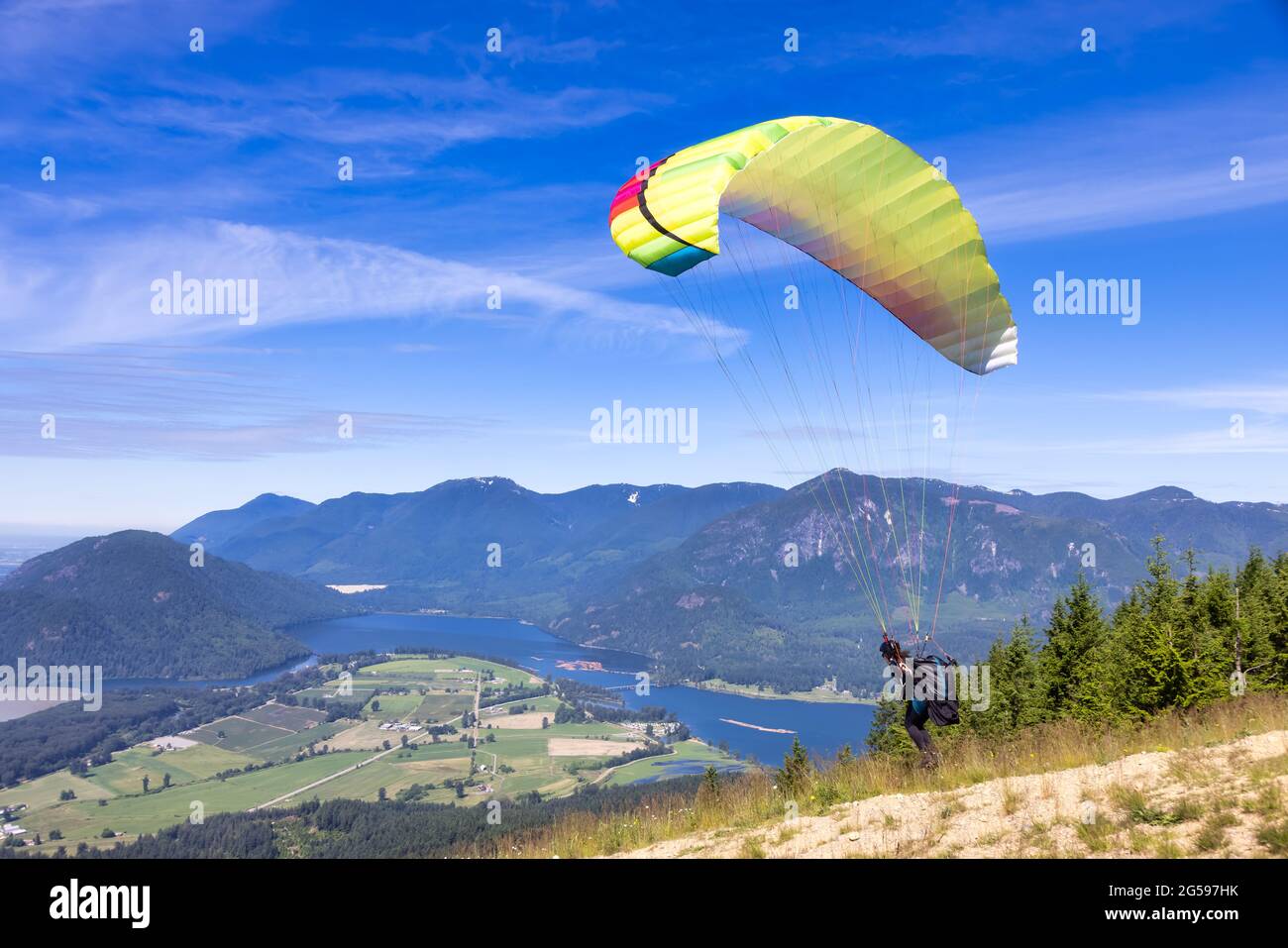 Adventurous Woman Flying on a paraglider around the Canadian Mountain ...