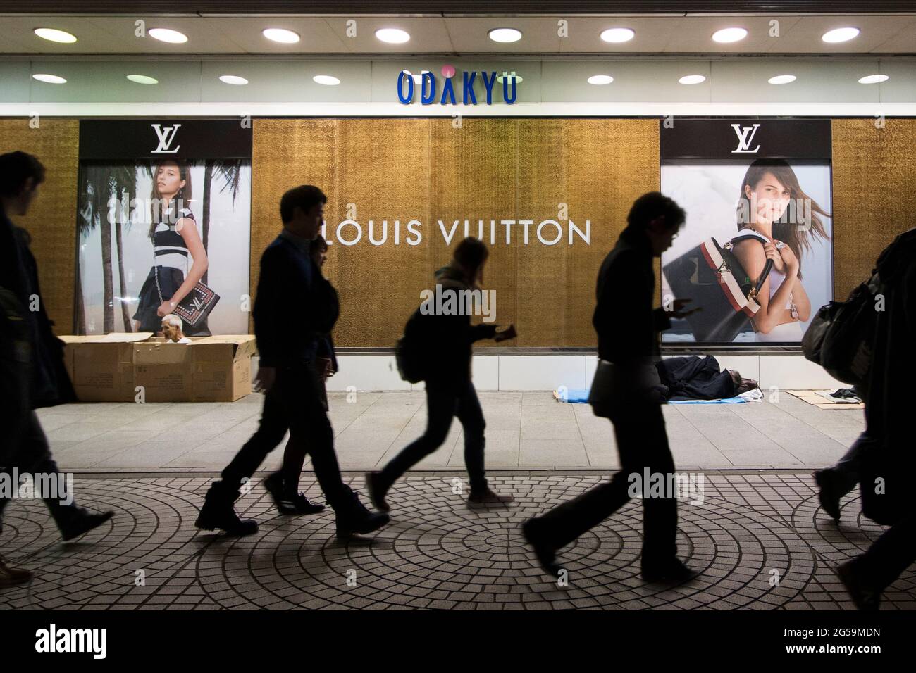 Commuters walking past homeless people sleeping outside the Odakyu ...