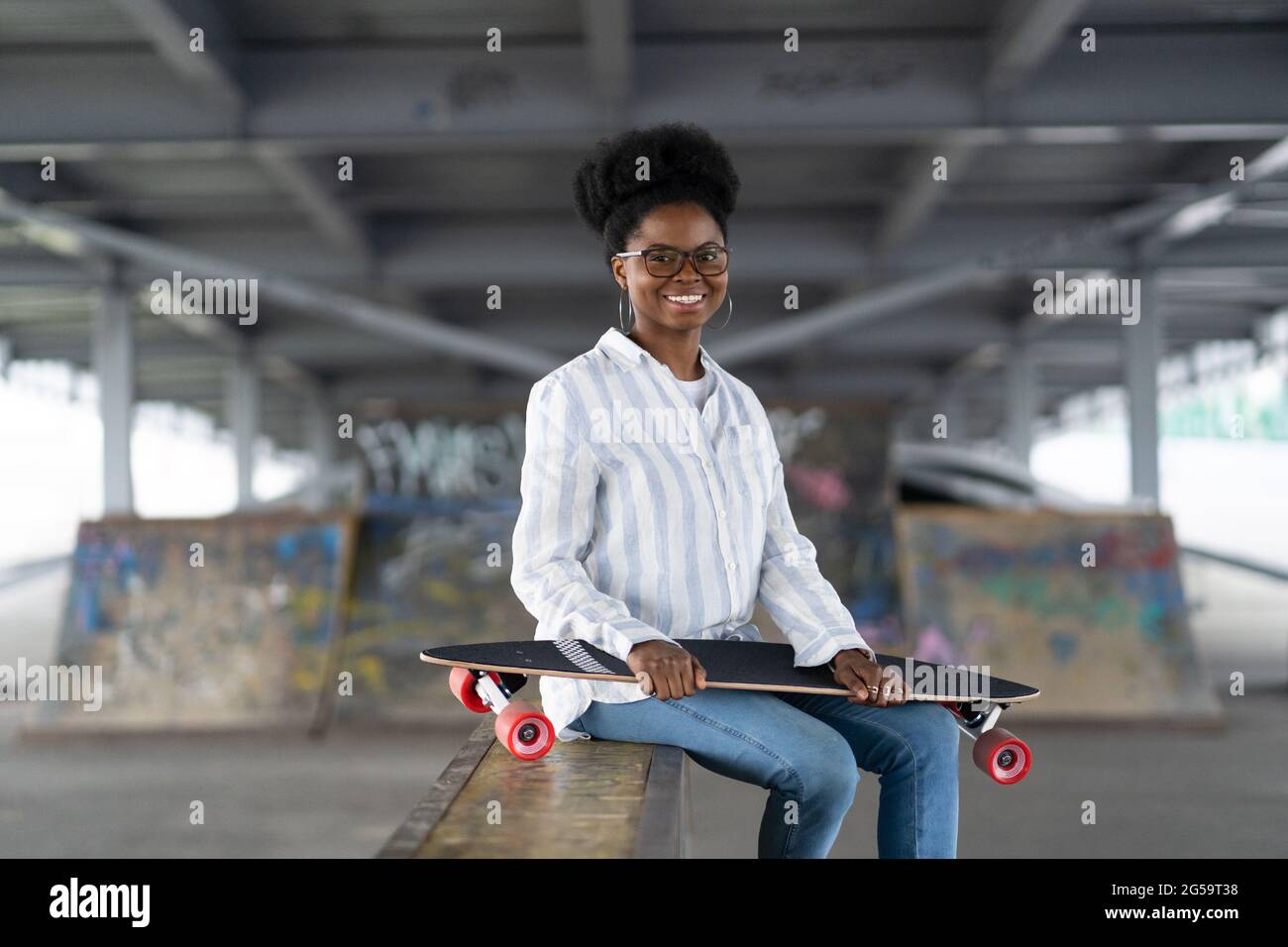 Happy african girl skater in skate park. Afro american young ...