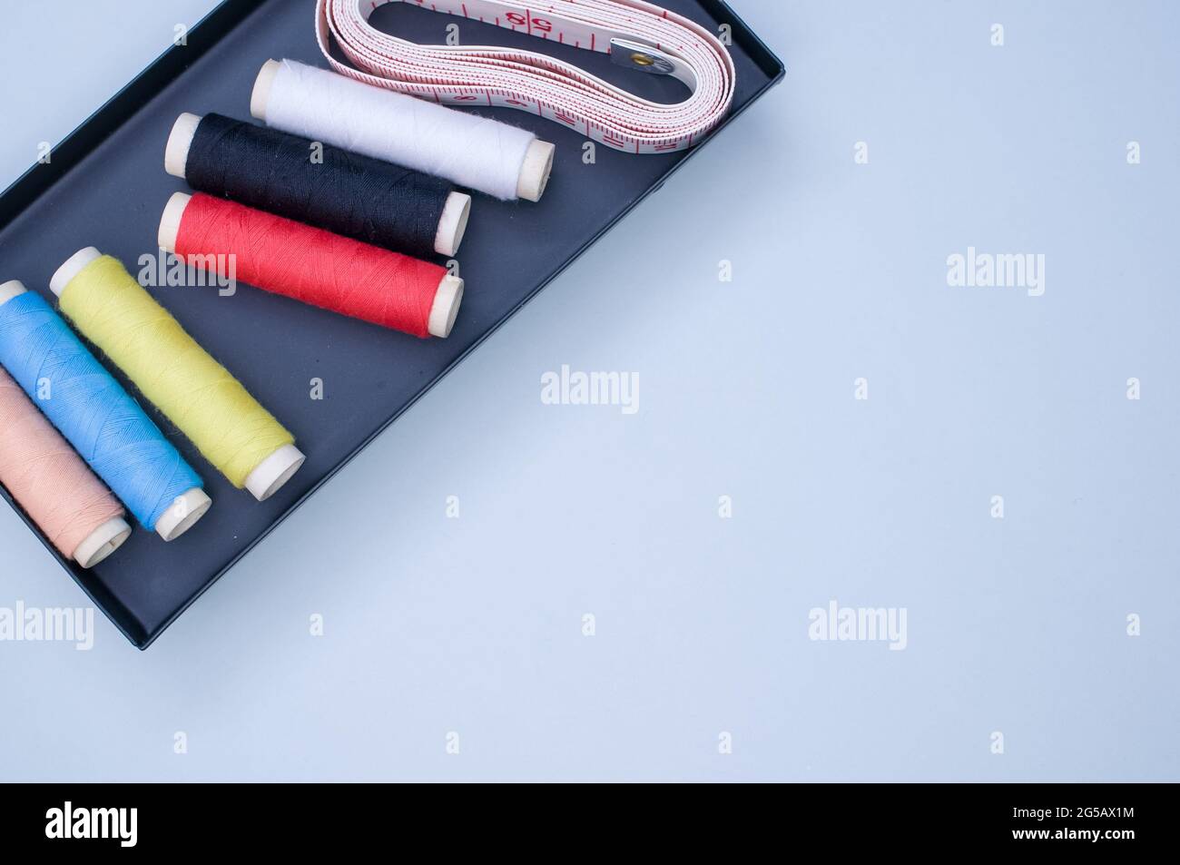 Pack of colorful sewing threads and a measuring tape on a blue ...