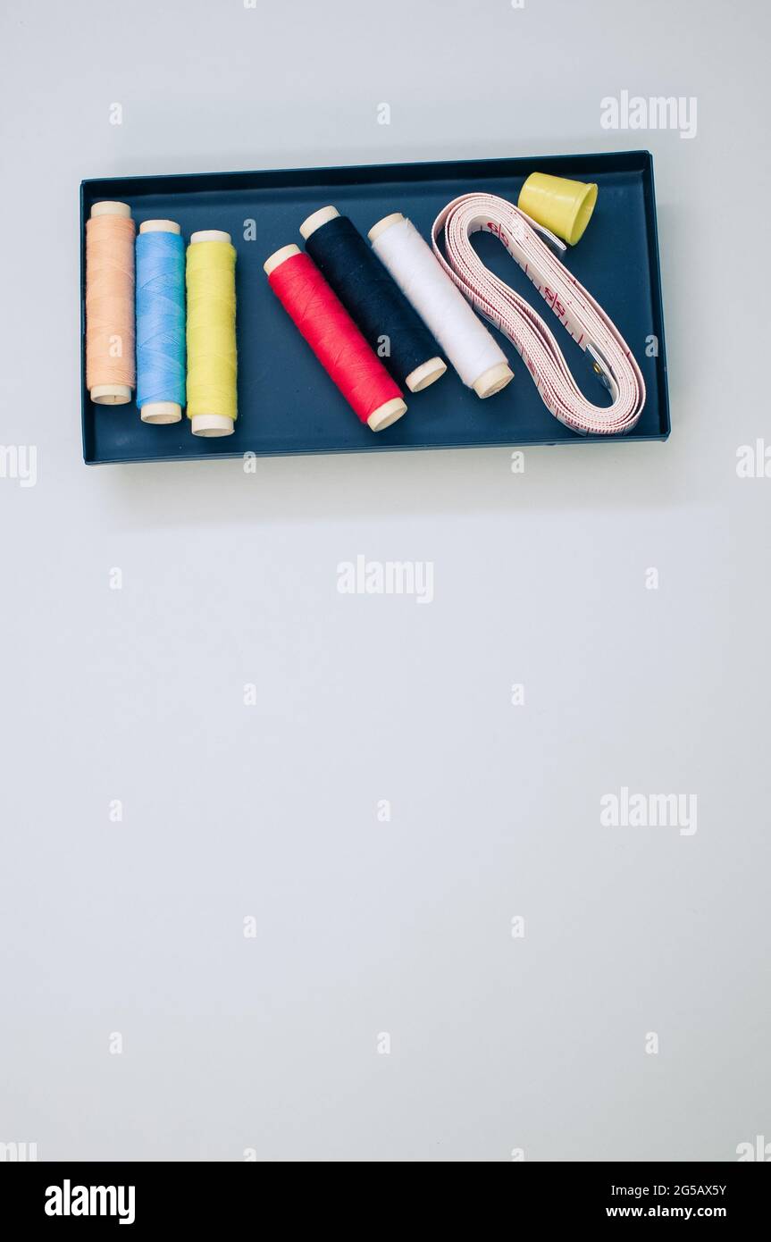 Pack of colorful sewing threads and a measuring tape on a clear ...