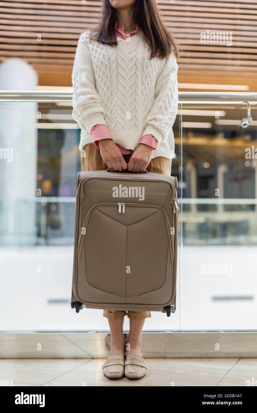 Unrecognizable female passenger holding suitcase posing at duty free ...