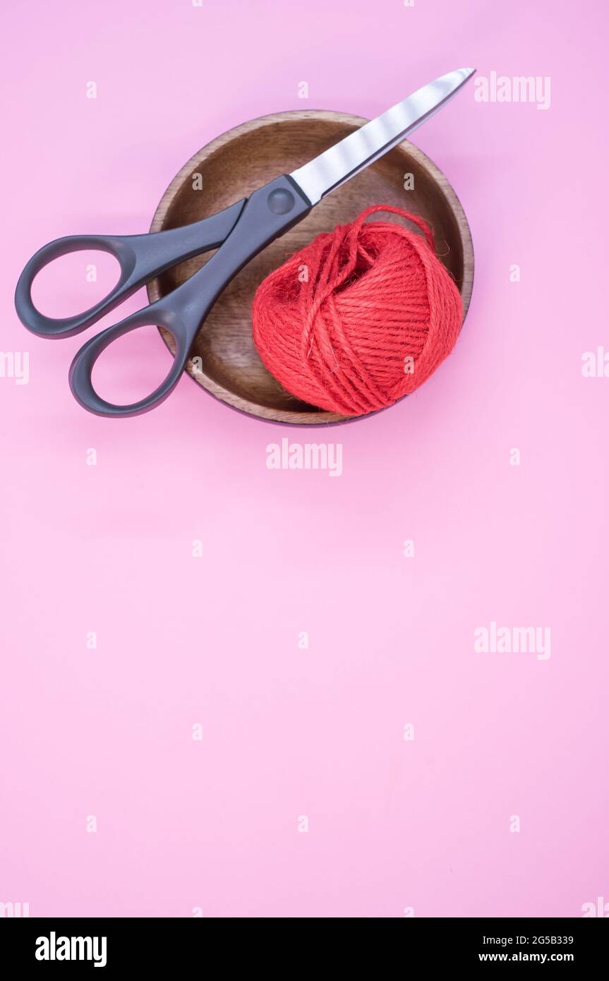Vertical shot of scissors and cotton yarn on a pink surface - copy ...