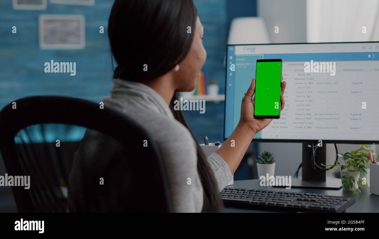 African woman analyzing social media video using mock up green screen ...