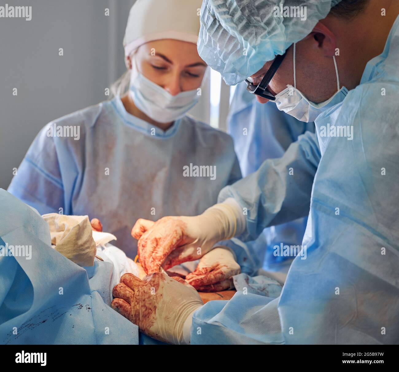 Doctors performing abdominoplasty surgery in clinic. Male plastic ...