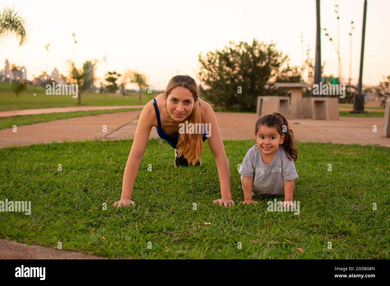 Young Hispanic fit female and her daughter exercising and posing on the ...