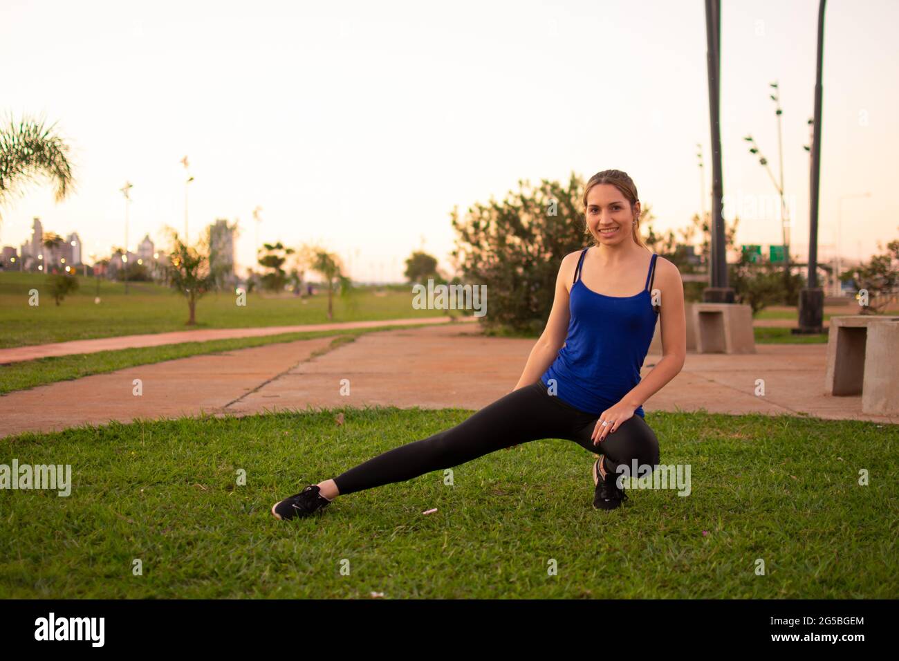 Hispanic fit female stretching and posing on grass Stock Photo - Alamy