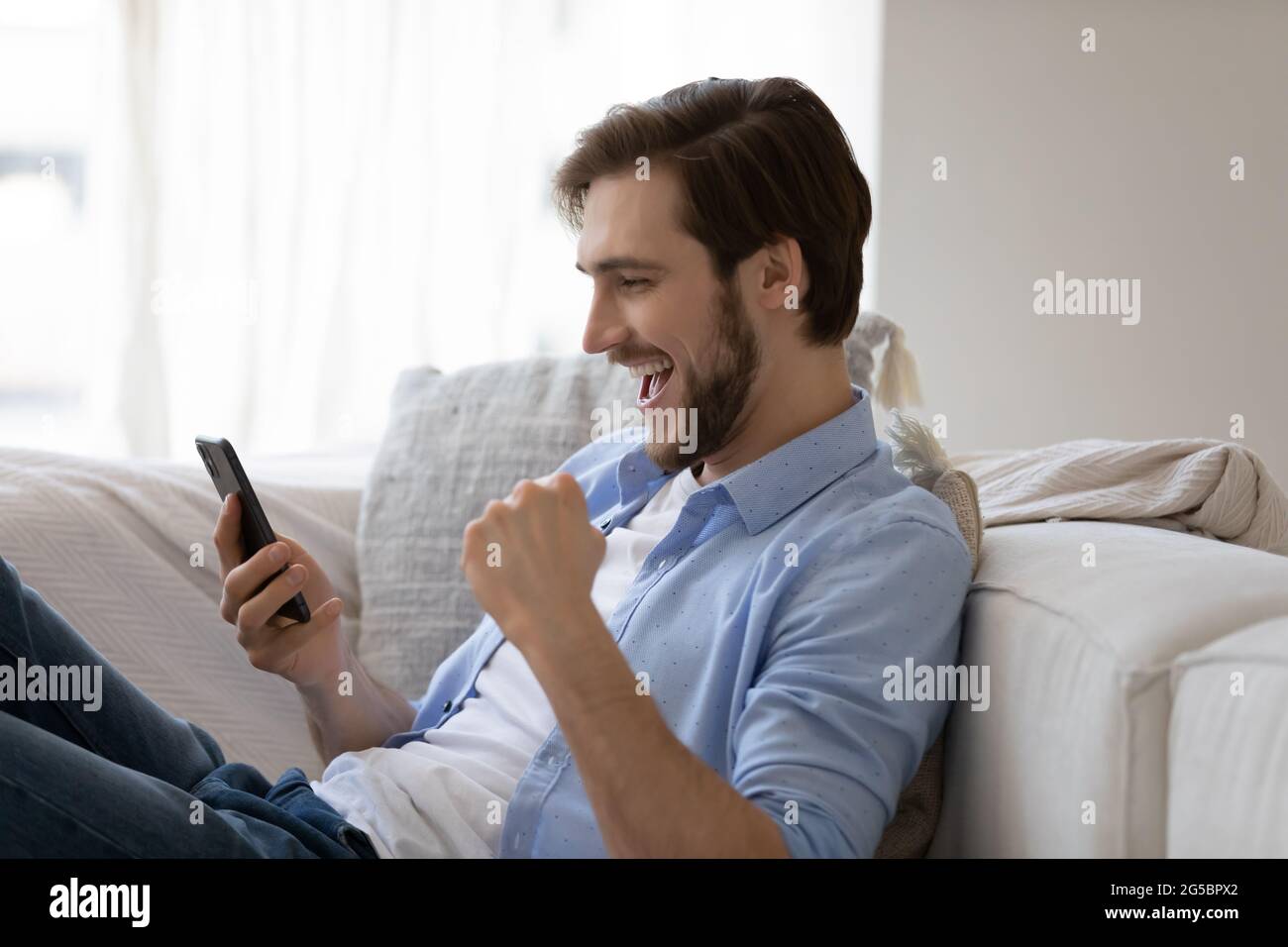 Excited happy man using mobile phone, getting surprising good news ...
