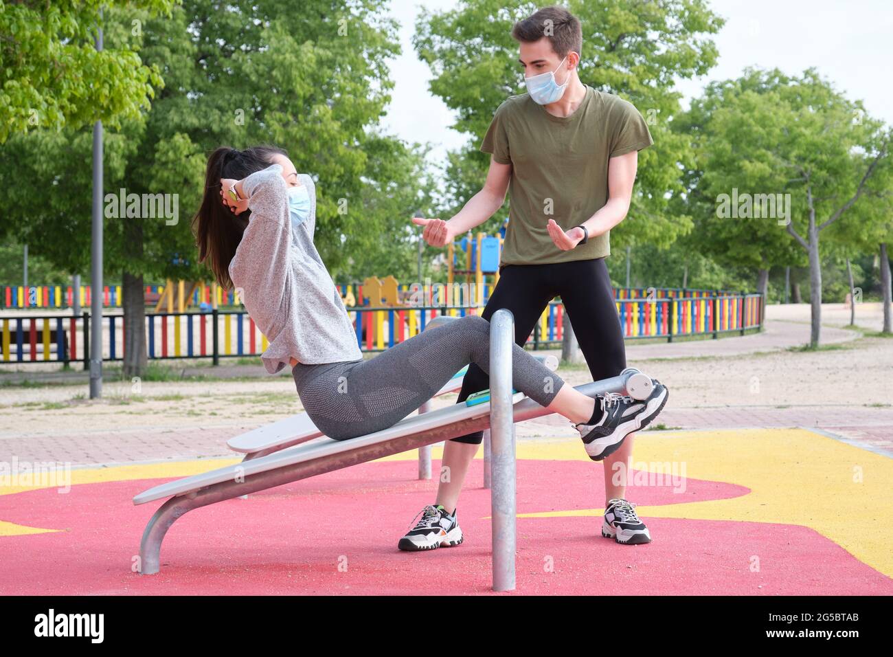 A woman doing abdominal crunches with her personal trainer at a ...