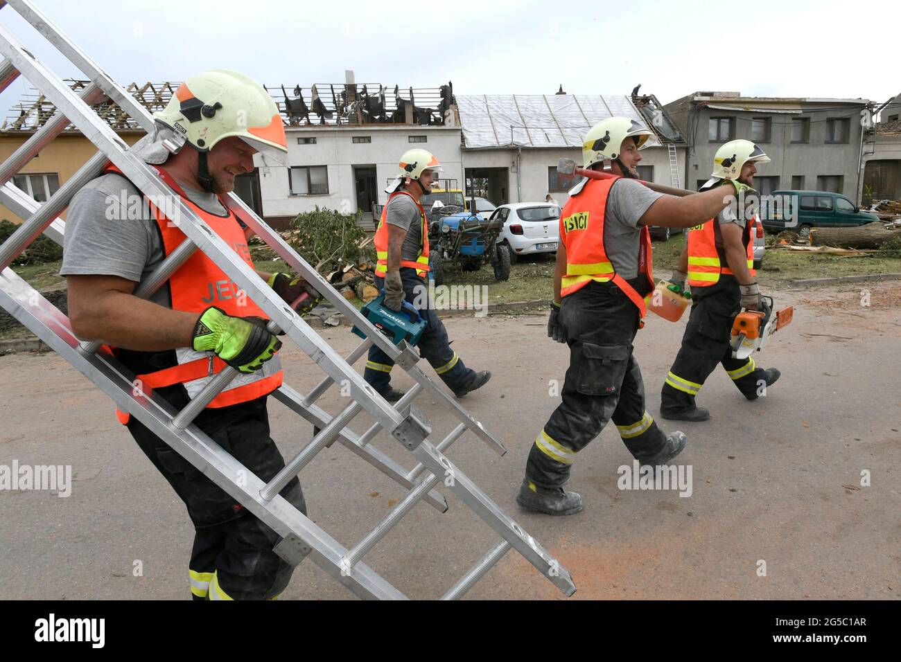 Firefighters clean debris from damaged houses after a tornado storm ...