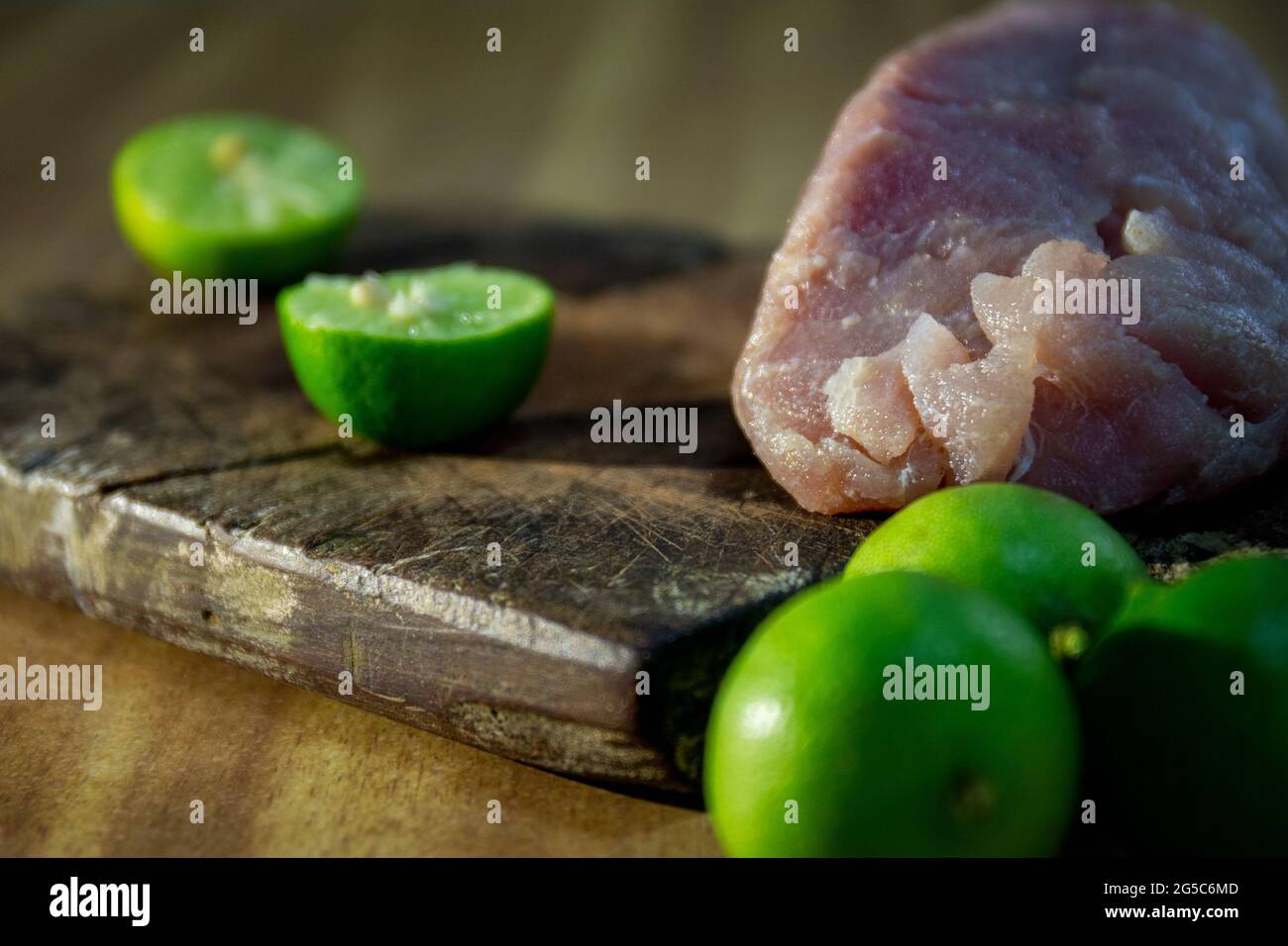Closeup of raw meat and fresh juicy limes on a cutting board Stock ...