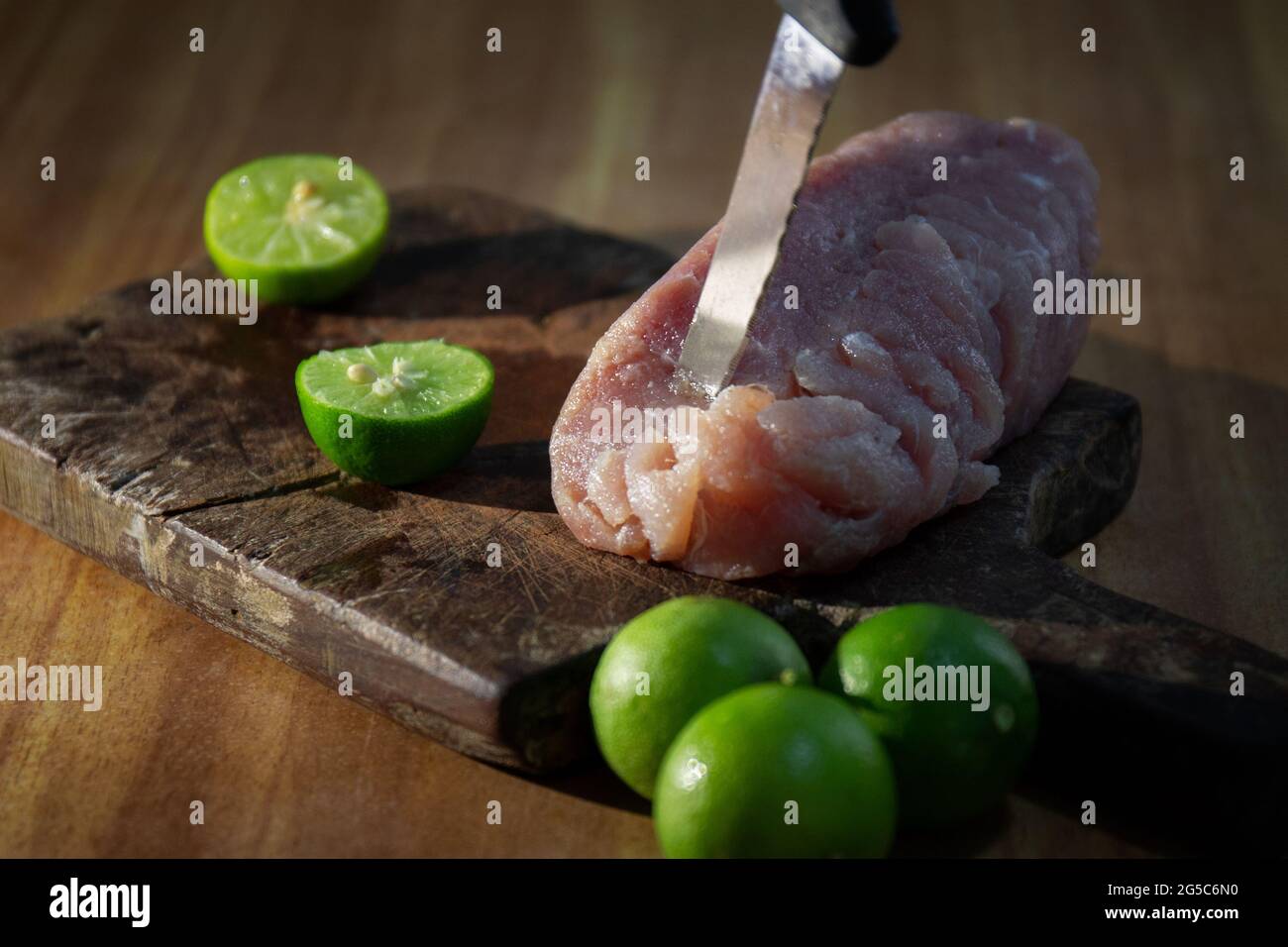 Closeup of raw meat and fresh juicy limes on a cutting board Stock ...