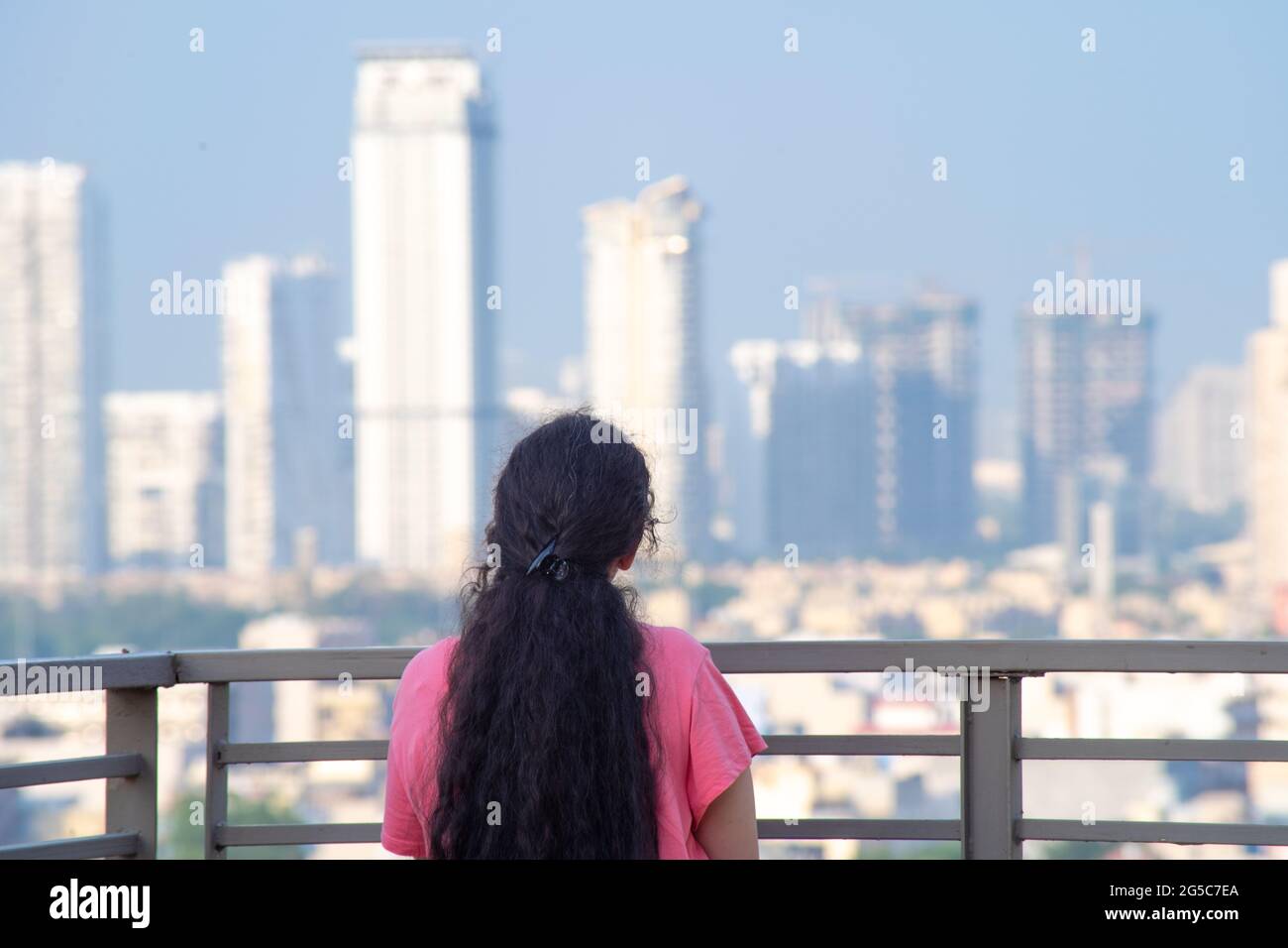 Zoomed in shot of indian woman with long hair in front of huge towers ...