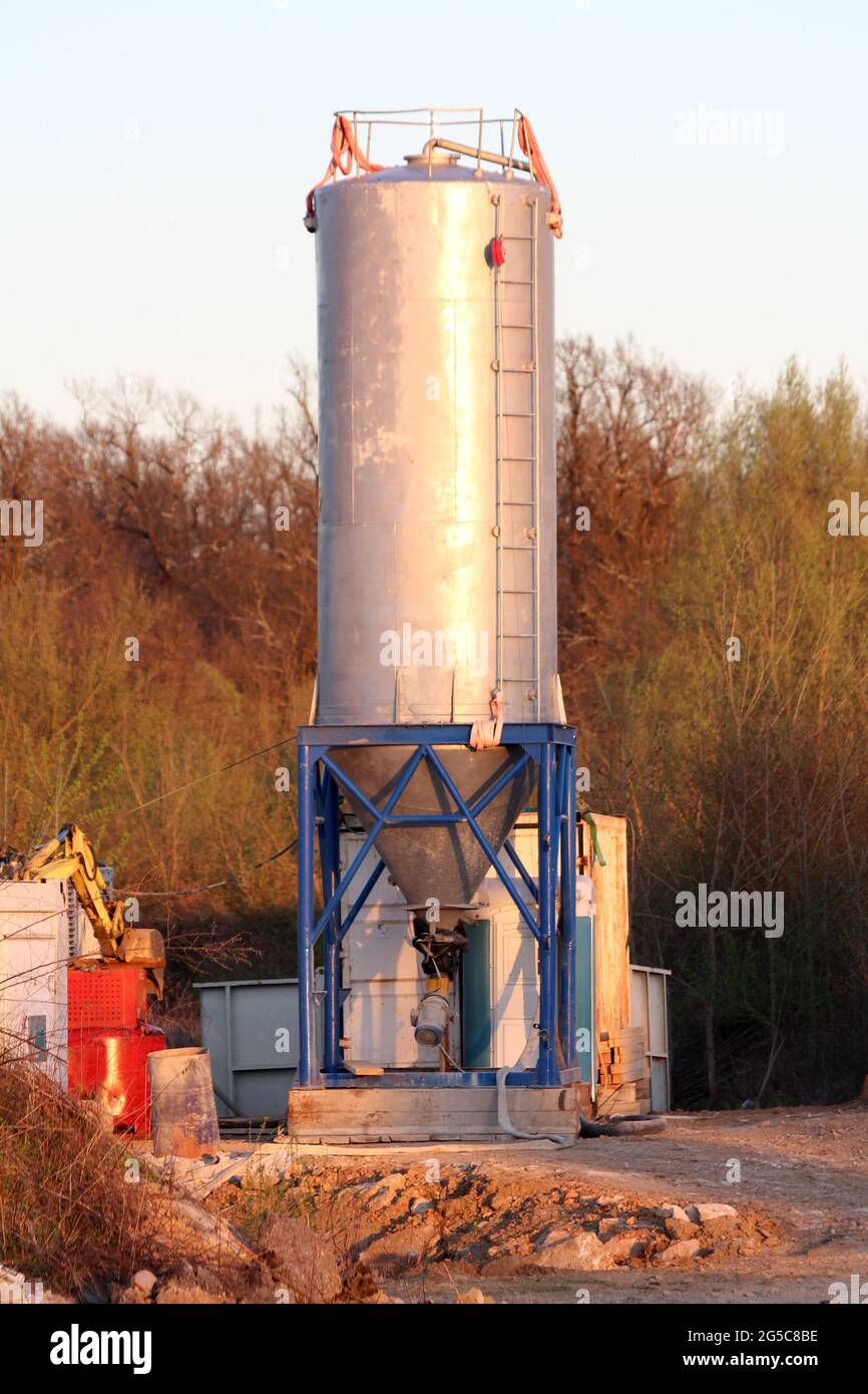 Shiny metal industrial storage silo on top of strong construction ...