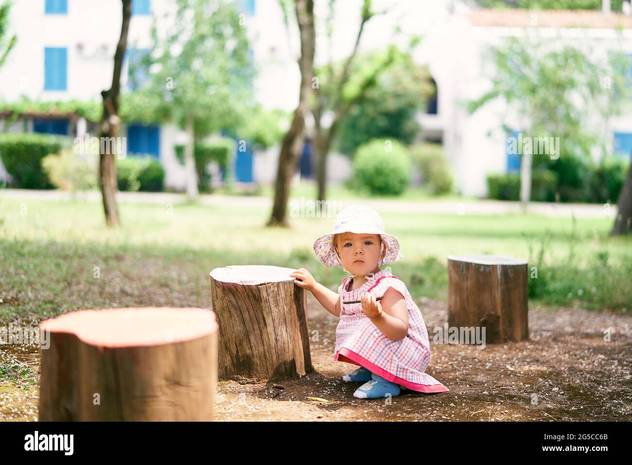 Little girl in a hat sat down near the stumps Stock Photo - Alamy