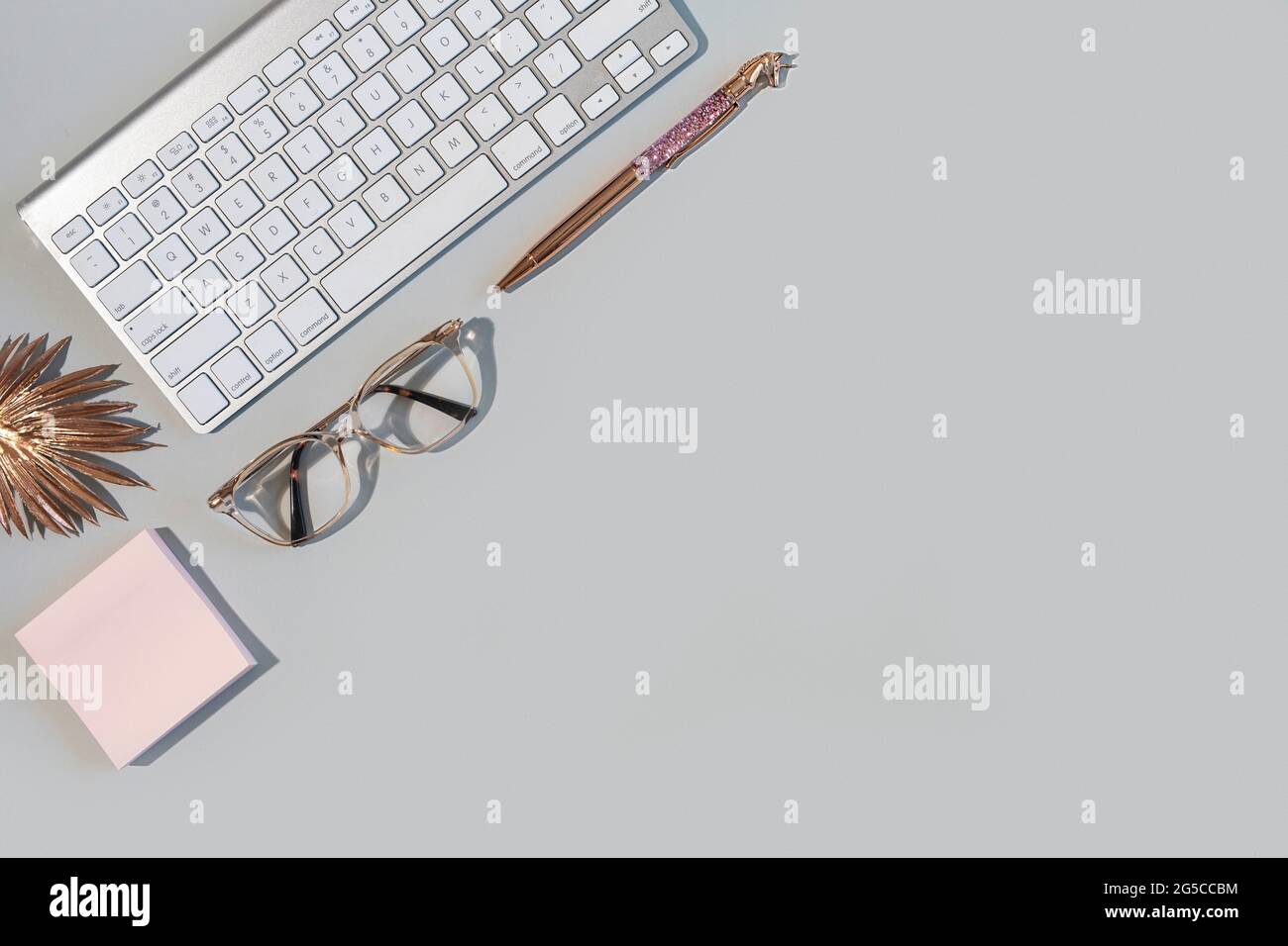 Overhead shot of business desktop with keyboard, glasses, pen on gray ...