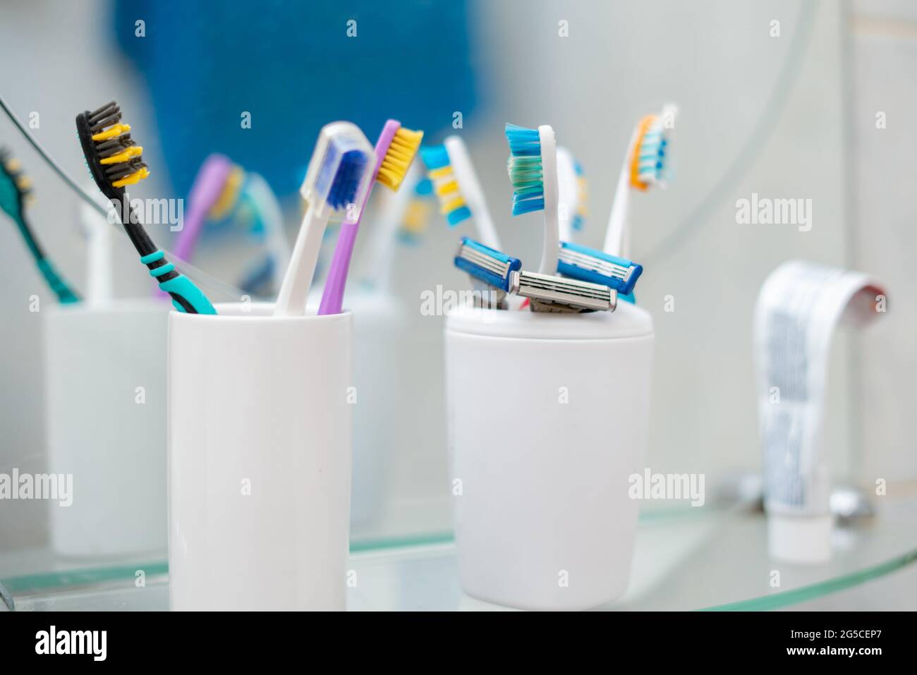 set of some colorful toothbrushes razor blades on the shelf in bathroom ...