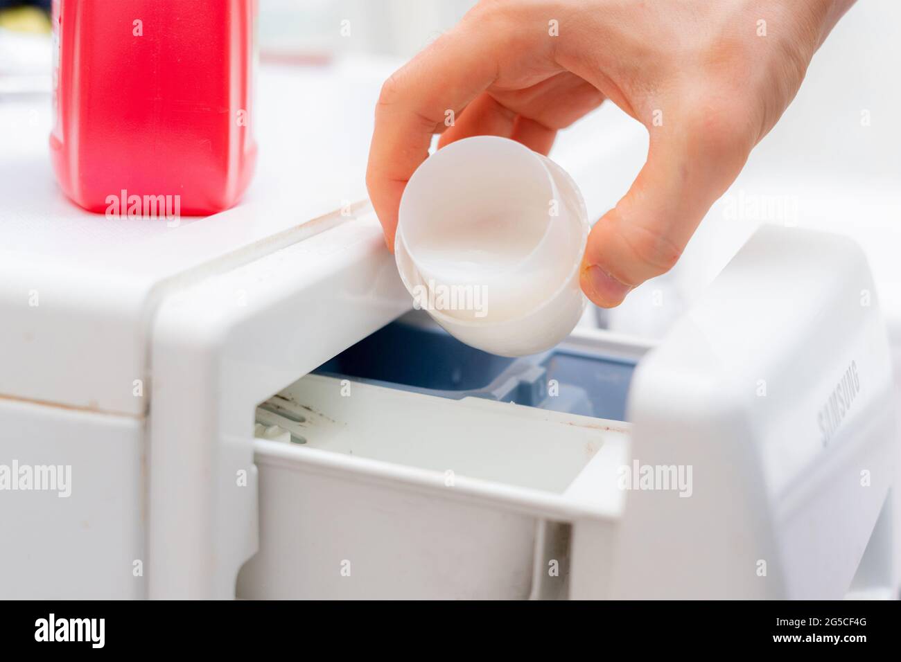 pouring the washing conditioner in the washing machine to get clean ...