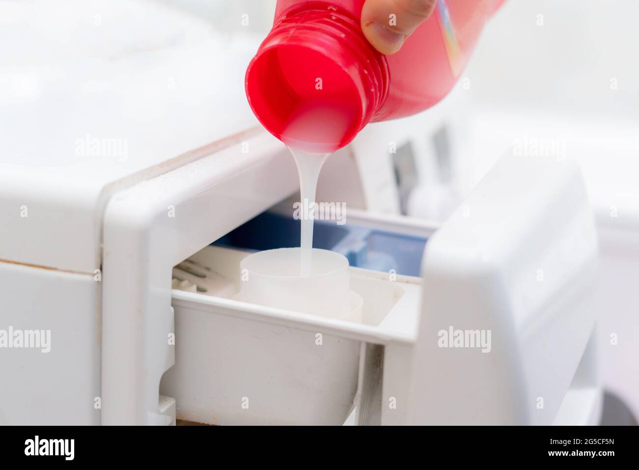 pouring the washing conditioner in the washing machine to get clean ...