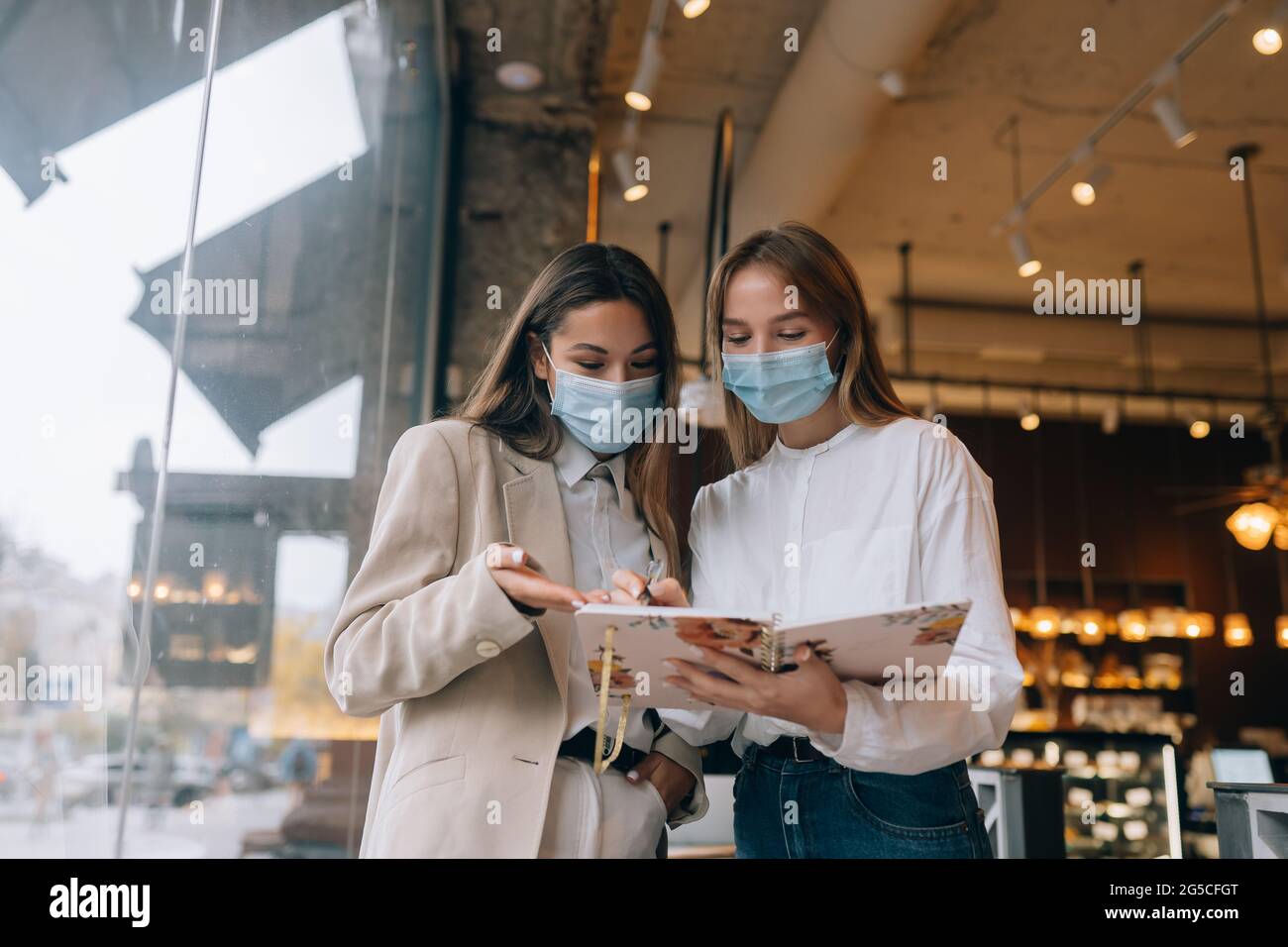 two businesswomen with their face masks debating different views on ...