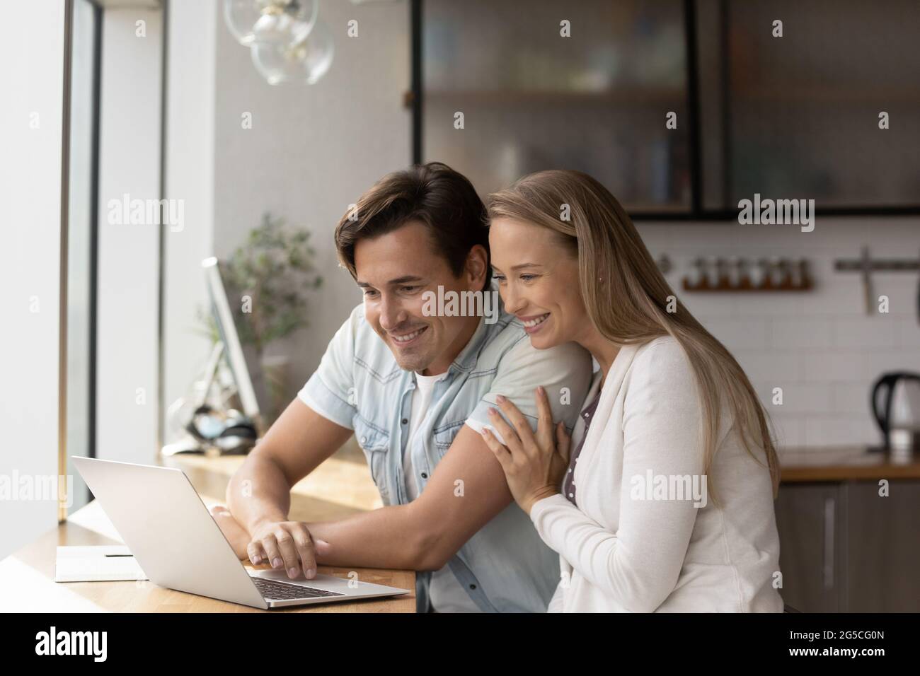 Happy affectionate couple using computer together in kitchen Stock ...
