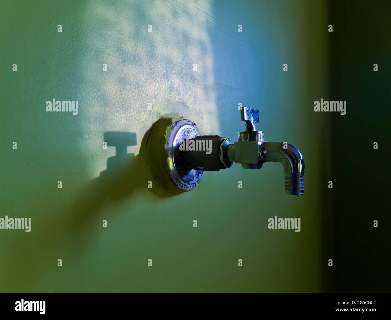 Simple metal water tap on the green wall Stock Photo - Alamy