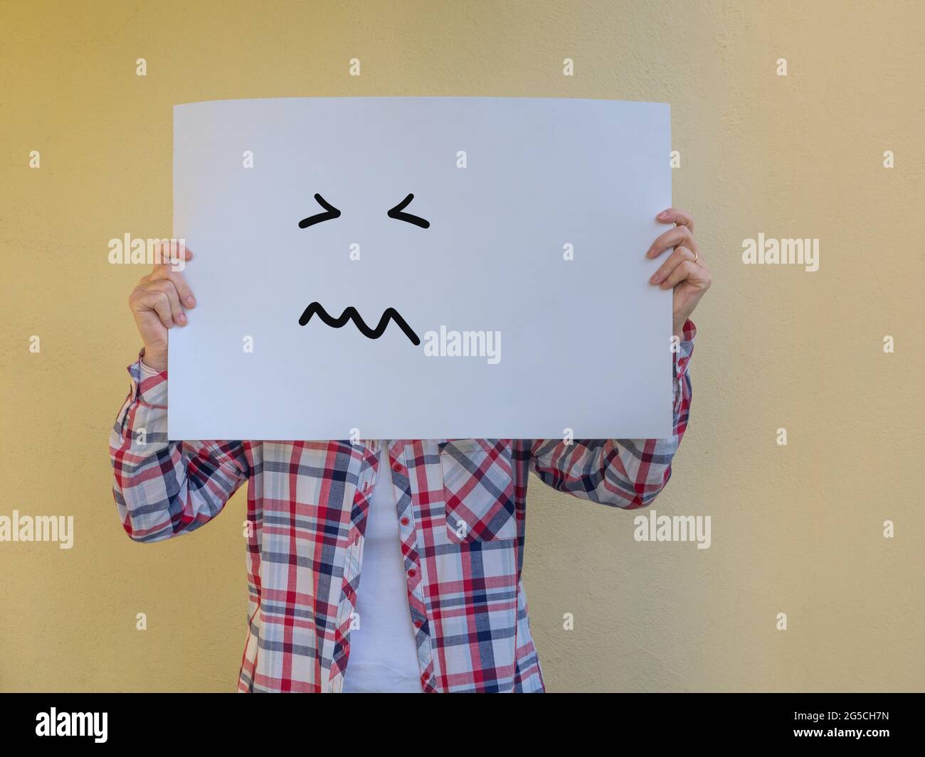 Casual woman hiding her face behind a blank billboard with a very angry ...