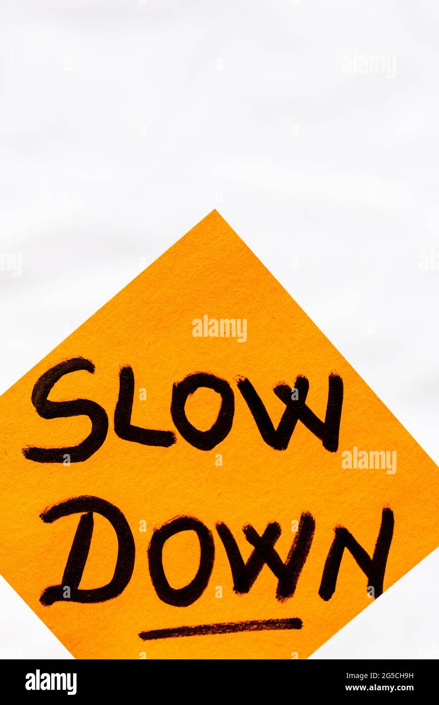 "Slow down" handwriting text on yellow paper in the white background ...