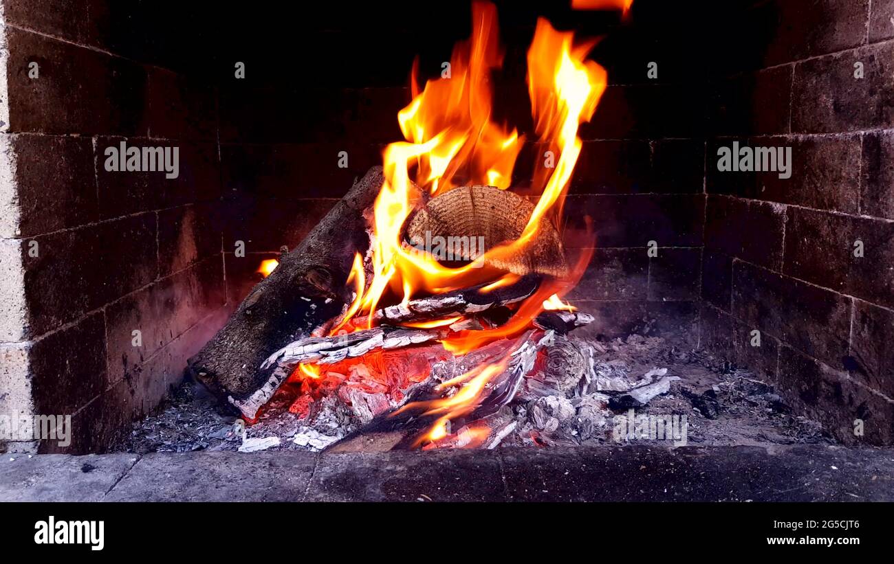 Closeup of flames on burning log in fireplace with smoke and glowing ...