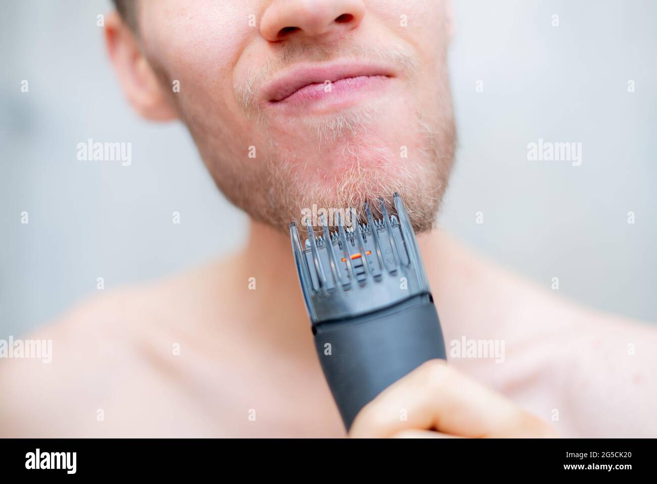 close up of young male person cutting his beard using the trimmer Stock ...