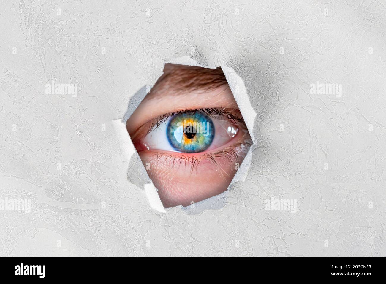the close up of eye looking through the torn paper hole Stock Photo - Alamy