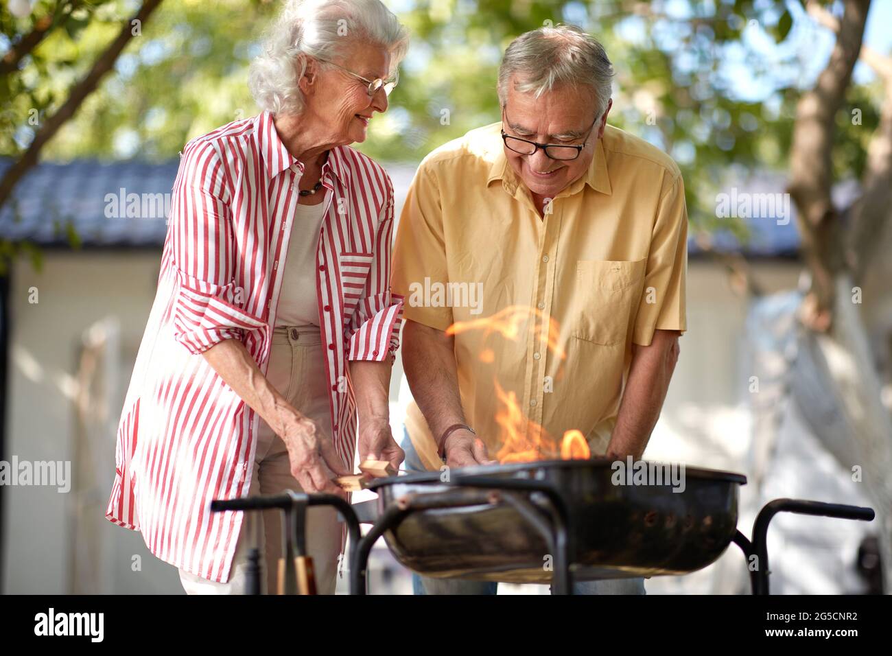 elderly caucasian couple making fire for barbeque Stock Photo - Alamy