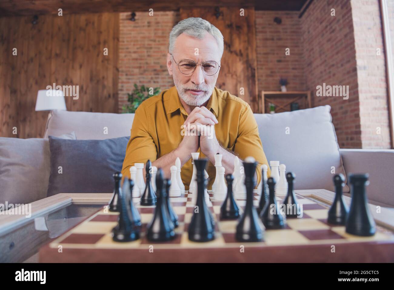 Photo of smart thinking mature man play chess wear spectacles yellow ...