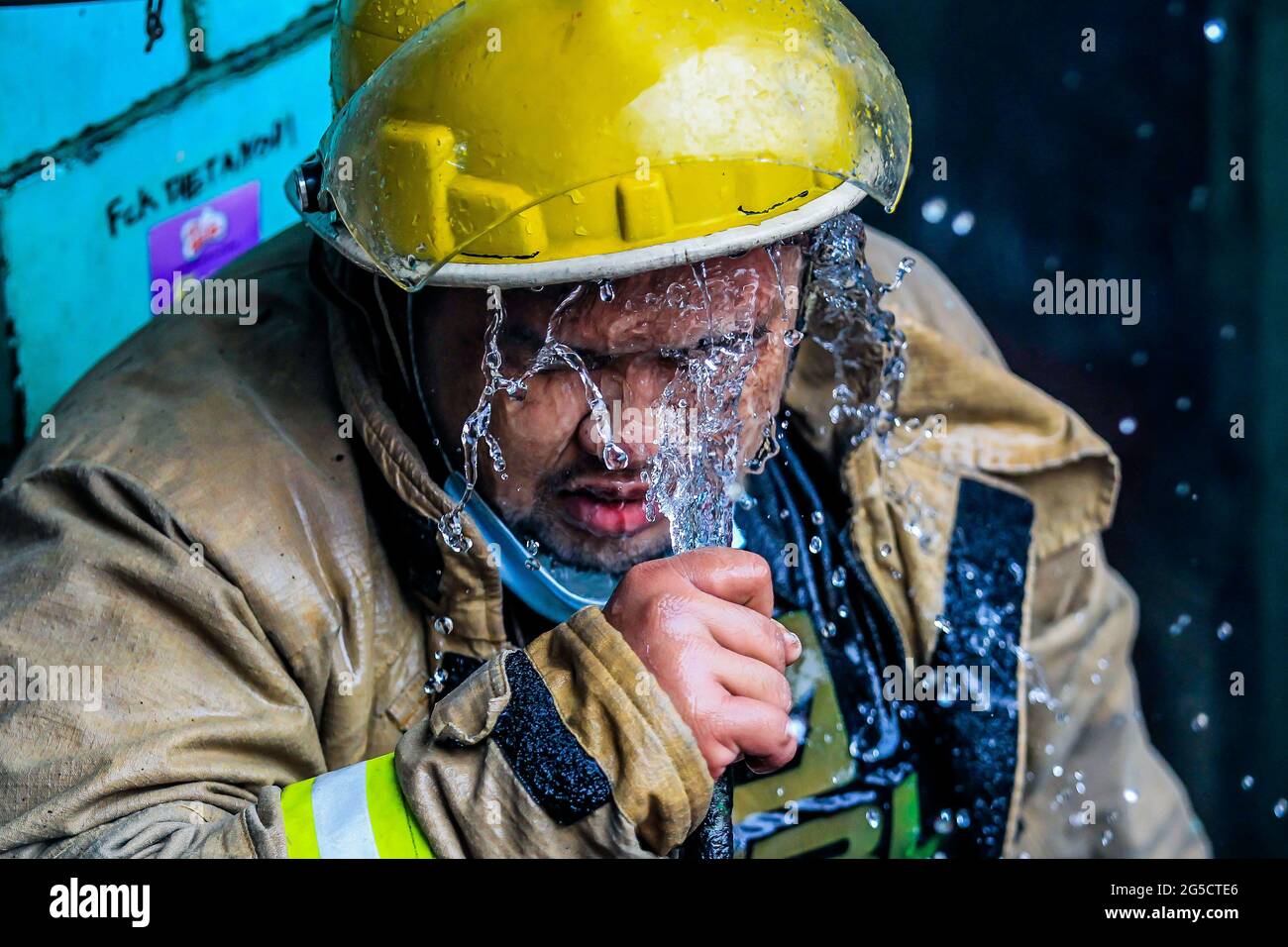 Quezon City. 26th June, 2021. A firefighter uses a water pipe to cool ...